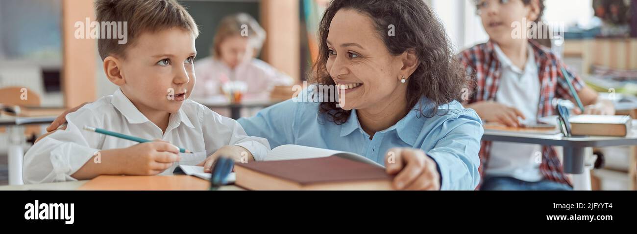 Happy kind teacher is helping a boy in elementary school lessons Stock ...