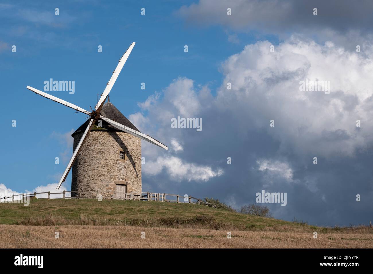 Windmill on top of a hill with a blue sky with white clouds, Normandy ...