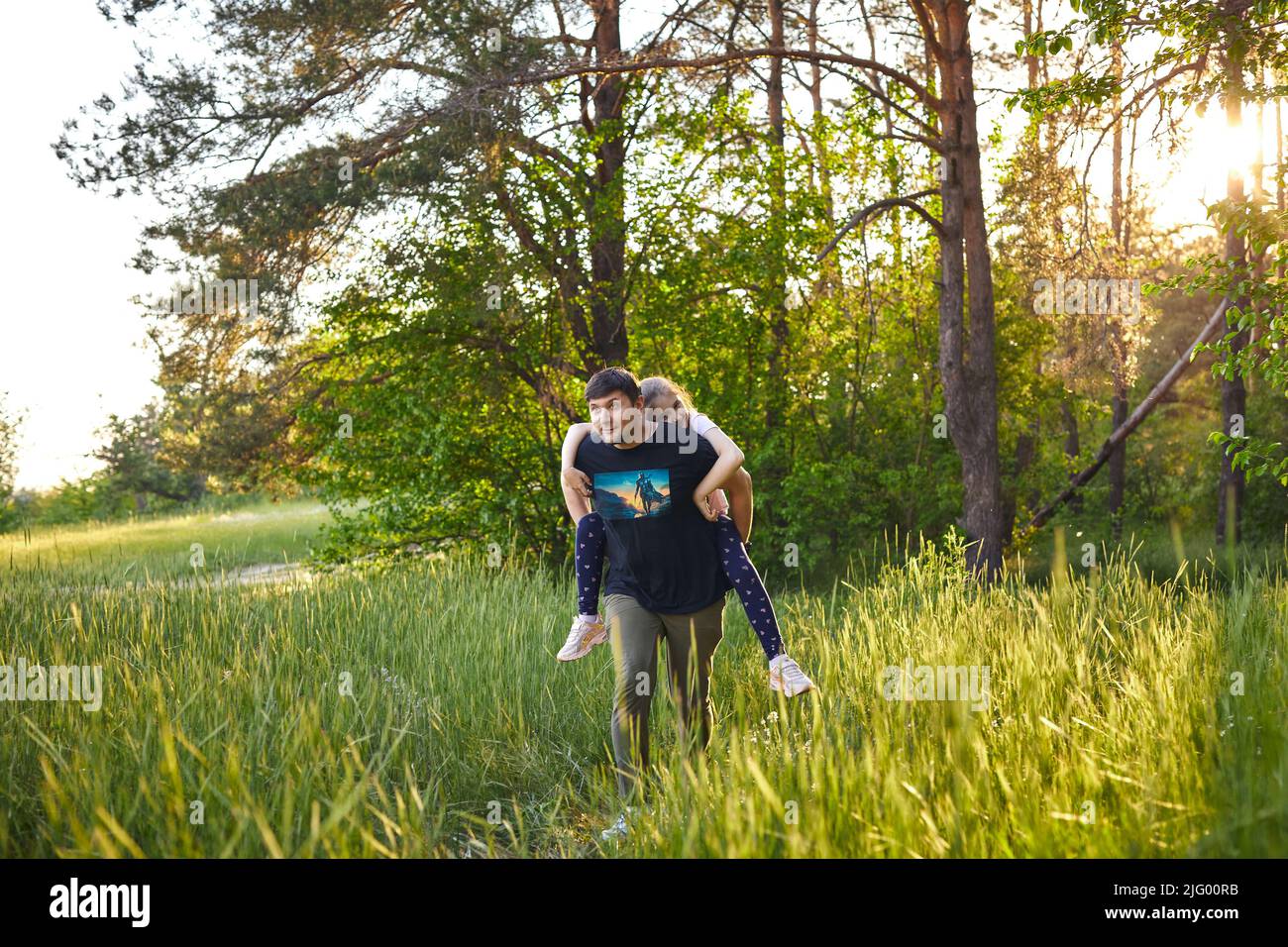 Father giving piggyback ride to small daughter on a walk in forest ...