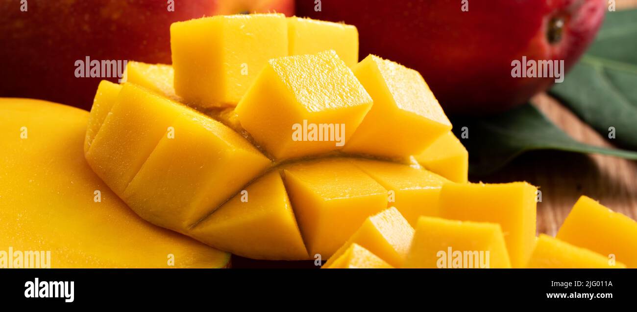 Mango. Close up of fresh ripe mango fruit with leaves over dark wooden ...