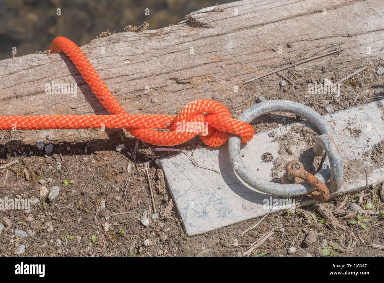 Sunny quayside with boat mooring rope attached to metal mooring ring ...