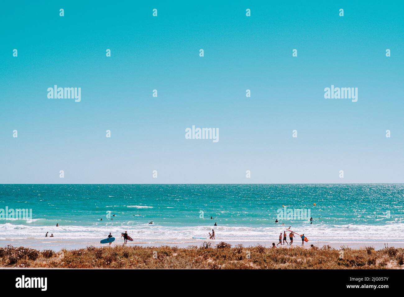 beach crowded with surfers and people sunbathing and playing games ...