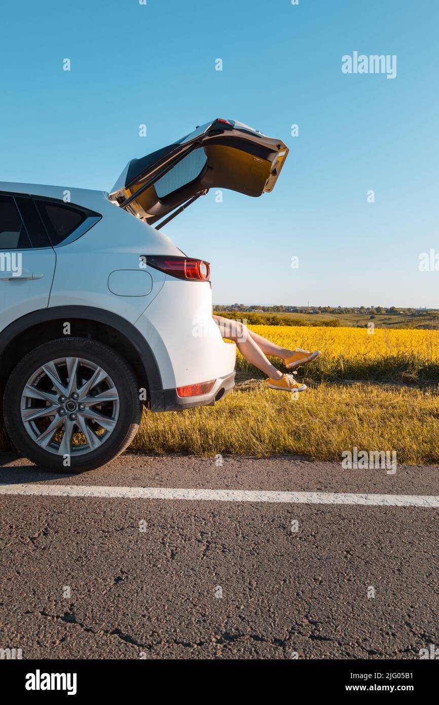 woman legs stick out of suv car trunk parked at roadside of speedway ...