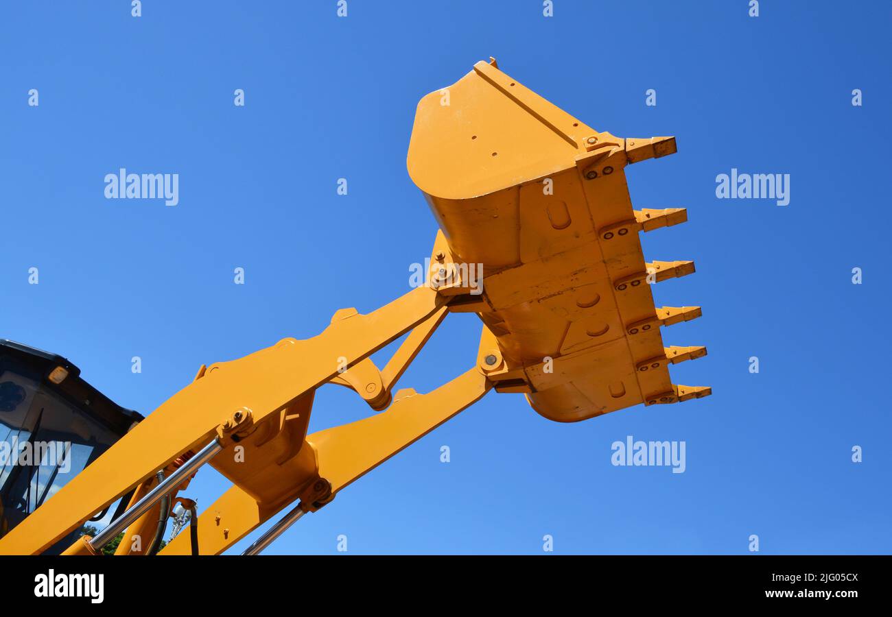 Bulldozer lifting bucket. Yellow excavator bucket against blue sky ...