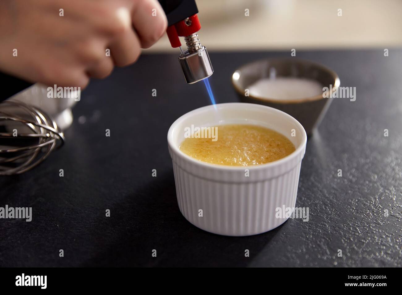 hand with burner making sugar crust in baking dish Stock Photo - Alamy