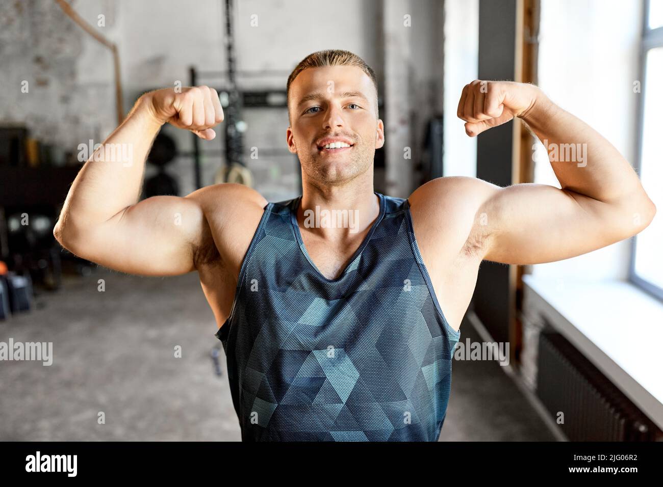 happy young man showing his bicep muscles in gym Stock Photo - Alamy
