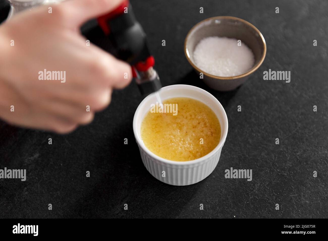 hand with burner making sugar crust in baking dish Stock Photo - Alamy