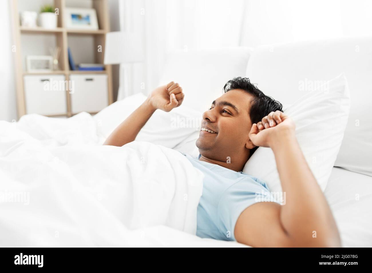 happy indian man stretching in bed at home Stock Photo - Alamy