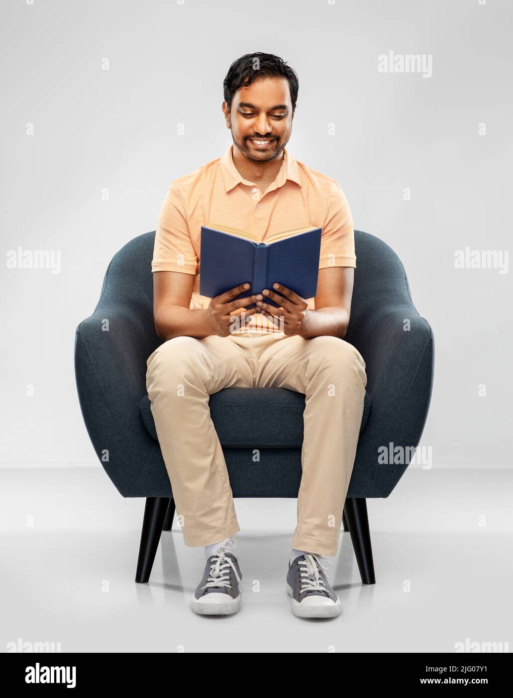happy young indian man reading book in chair Stock Photo - Alamy