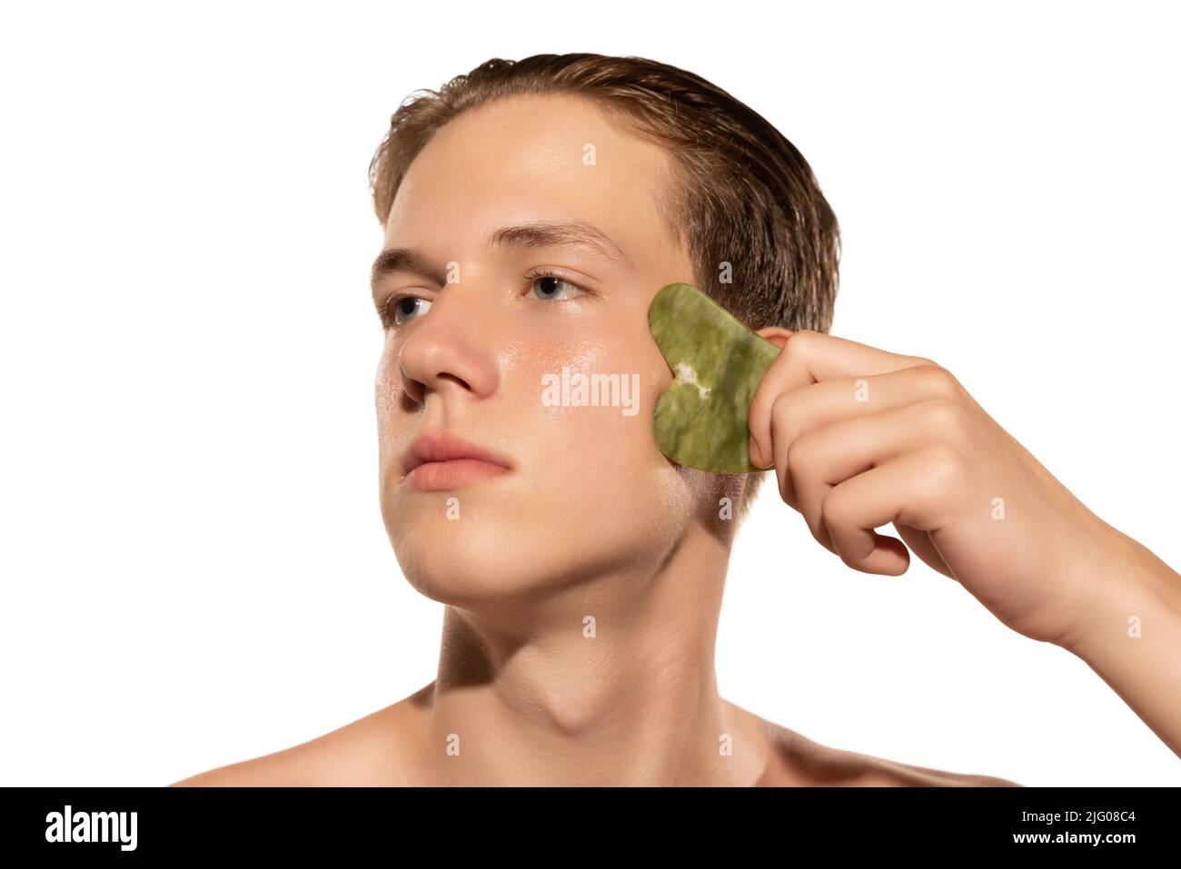 Young attractive man with perfect smooth skin, applying face massagers ...
