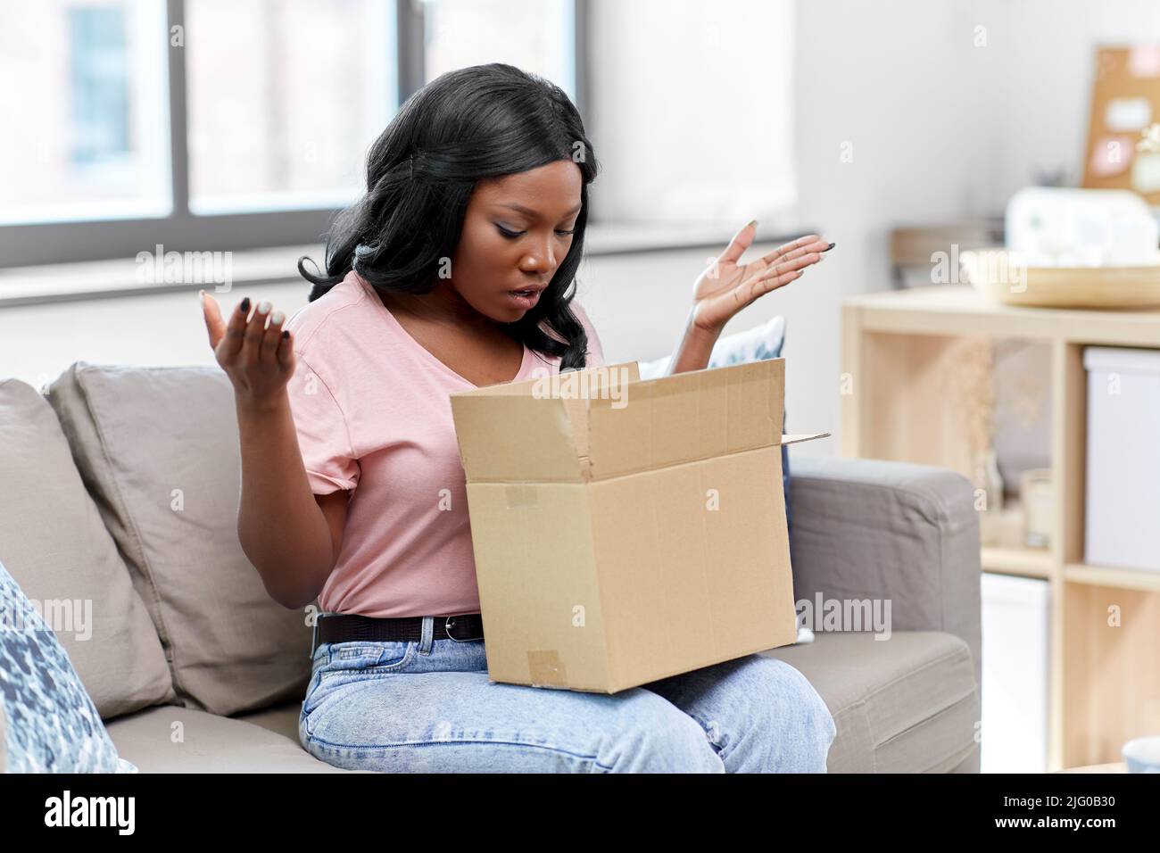 sad african american woman with parcel box at home Stock Photo - Alamy