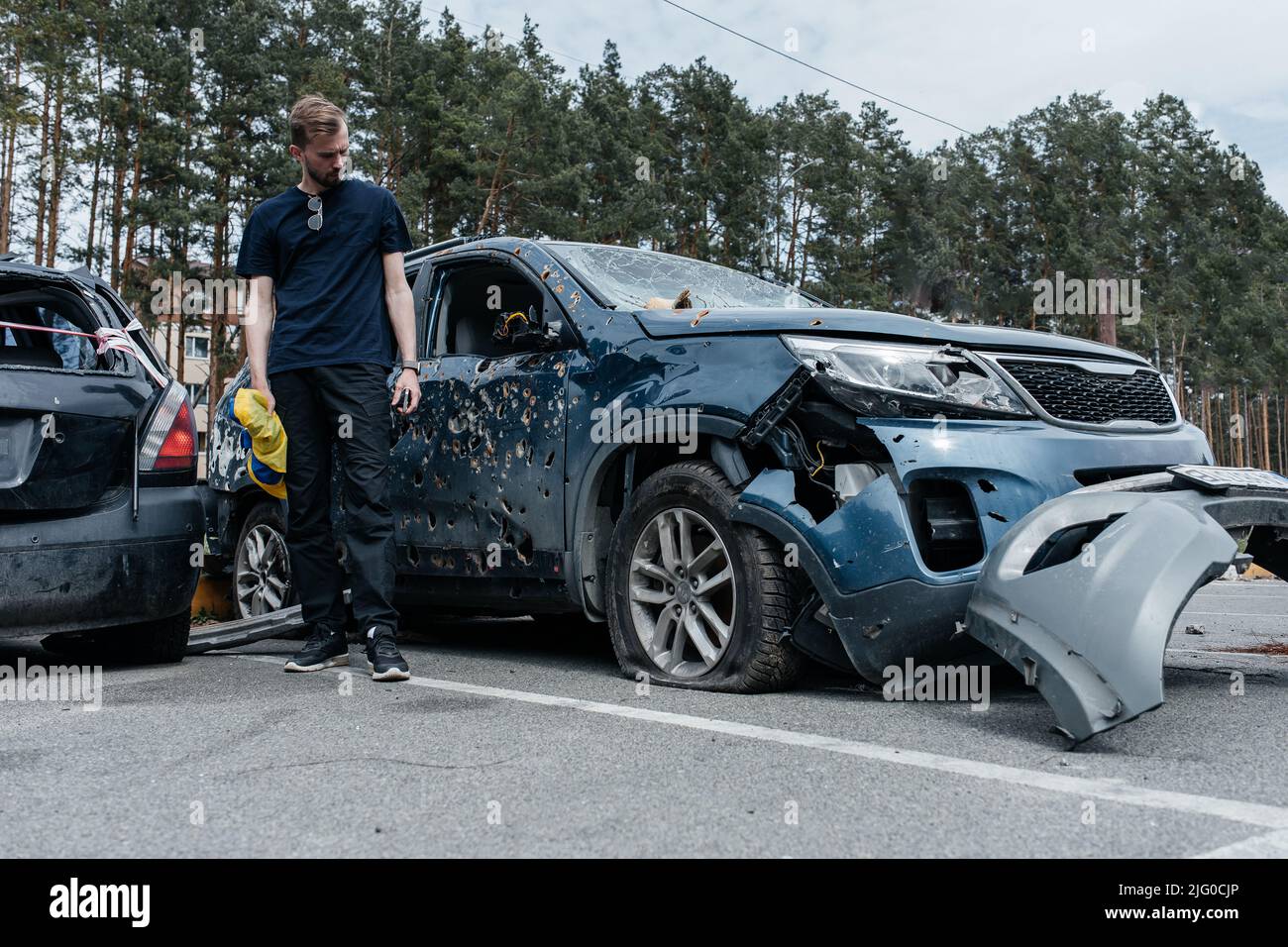 Man stands near shot damaged car riddled with bullets. Car shot by the ...