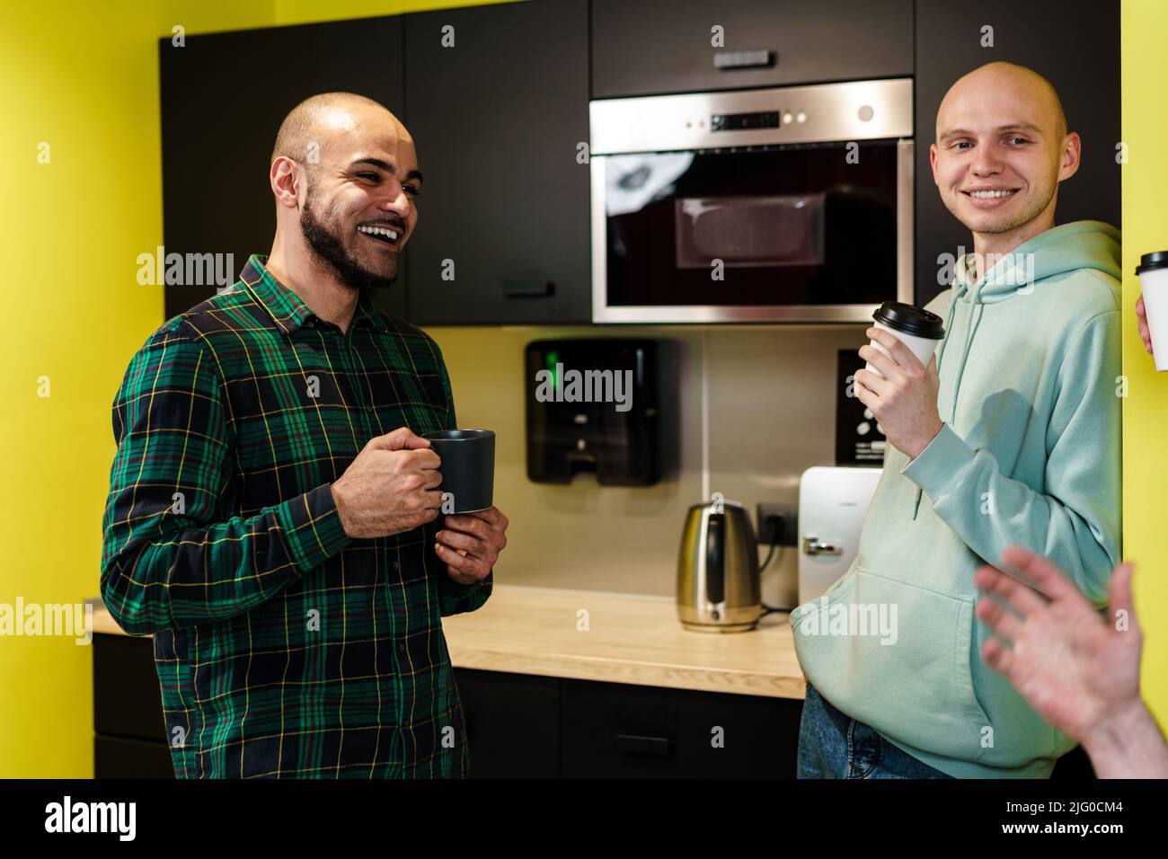 Two male colleagues having a talk while coffee break in office Stock ...