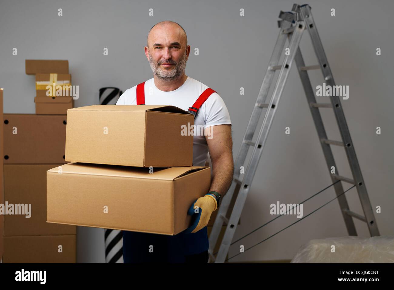 Middle-aged man mover in uniform holding cardboard box, portrait Stock ...