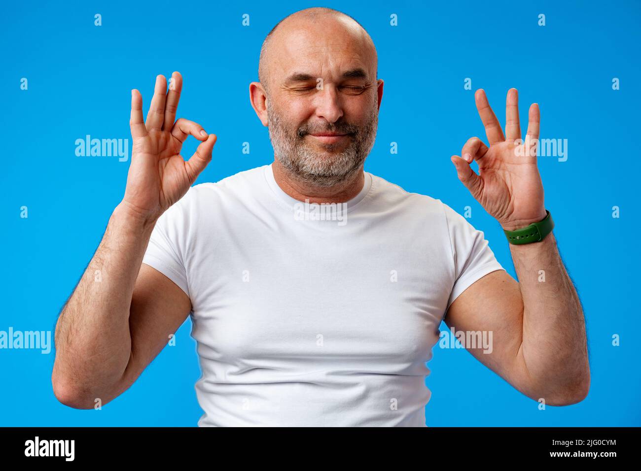 Meditating mature man on blue background in studio Stock Photo - Alamy