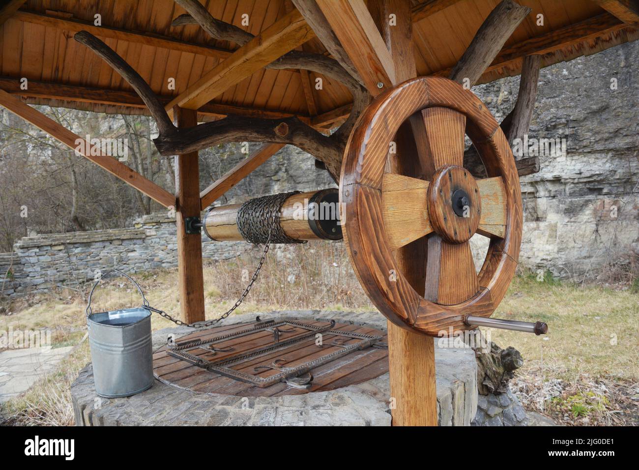 A close-up of a wooden well with a wooden well pulley, wheel and a ...