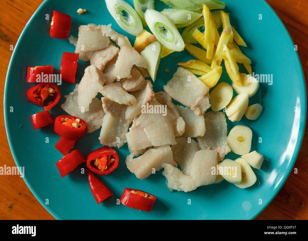 In the blue plate, there is hot water blanched pork, sliced garlic and ...