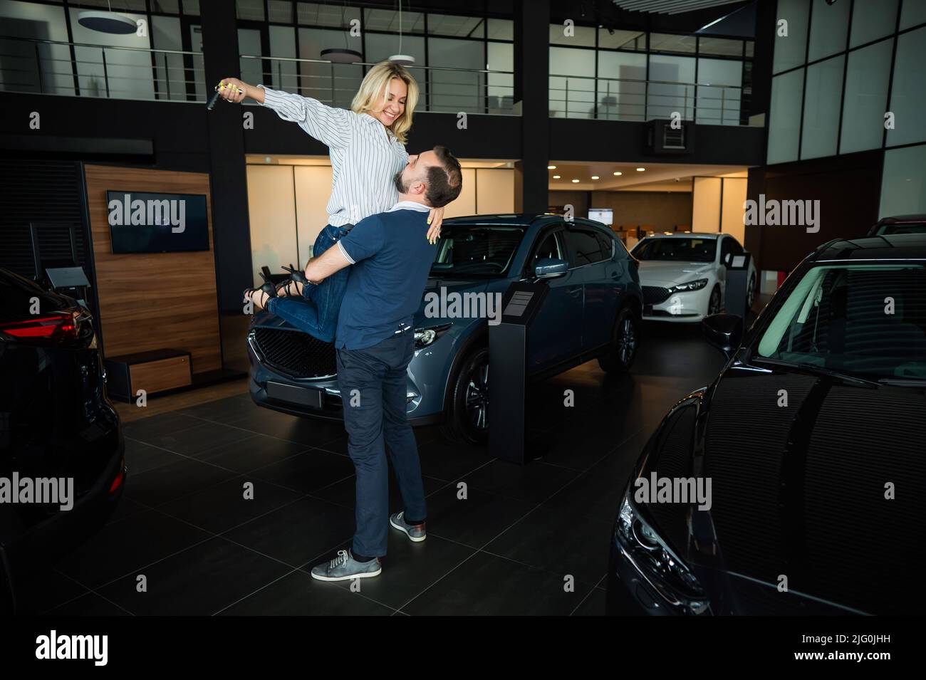 Happy caucasian couple hugging while buying a new car in a car ...
