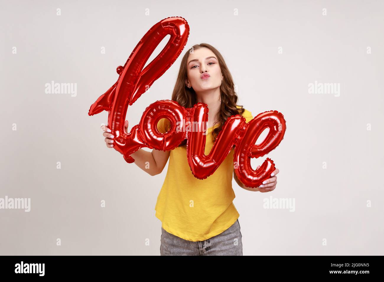 Playful teenager girl with foil word love in hands, looking at camera ...