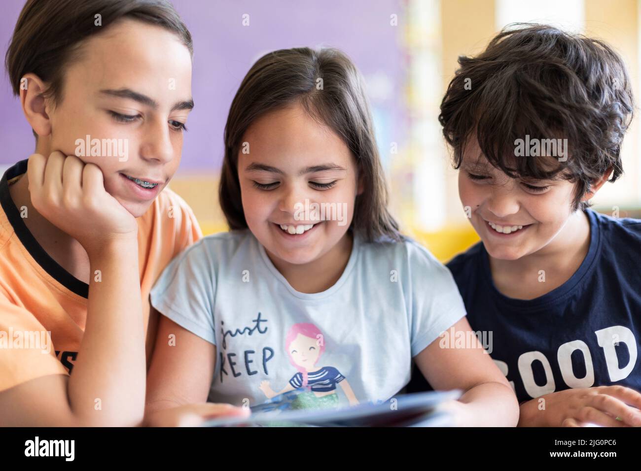 Three caucasian school children having a fun time in class while ...