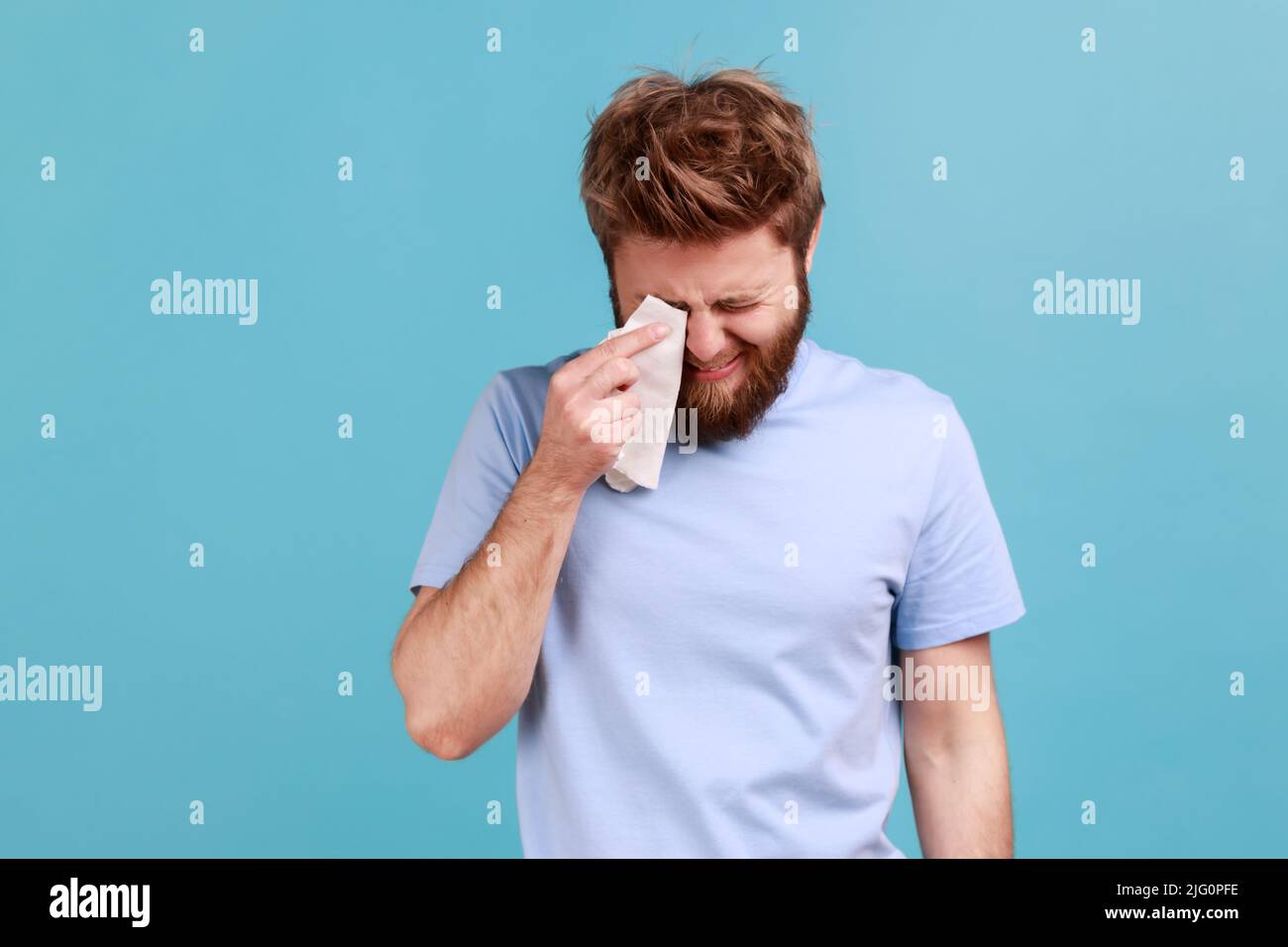 Portrait of unhappy frustrated bearded man sobs and rubs tears with ...