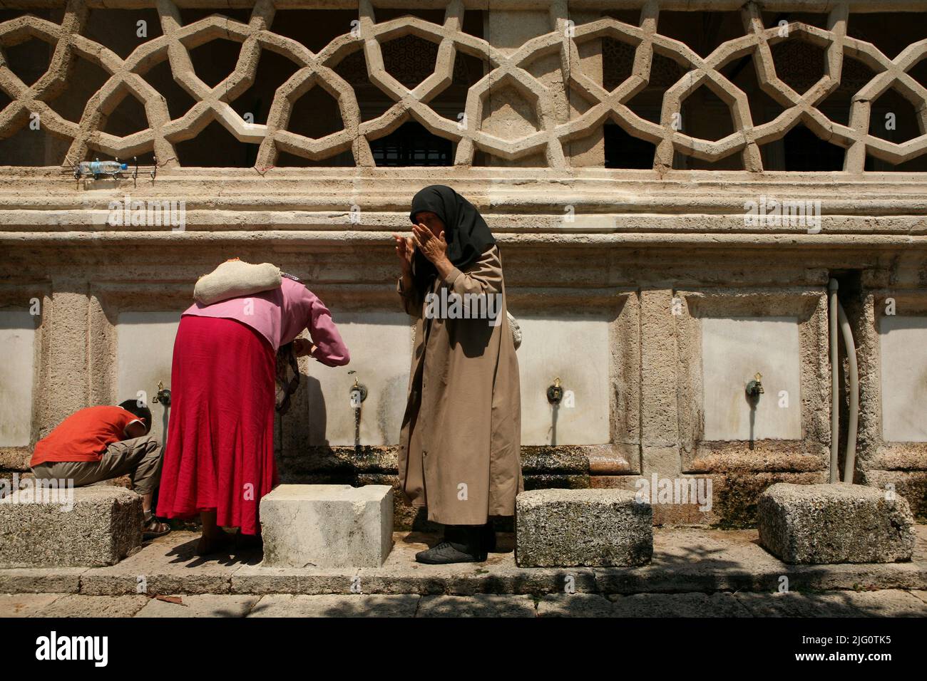 Muslim women washing their faces and hands before entering the mosque ...