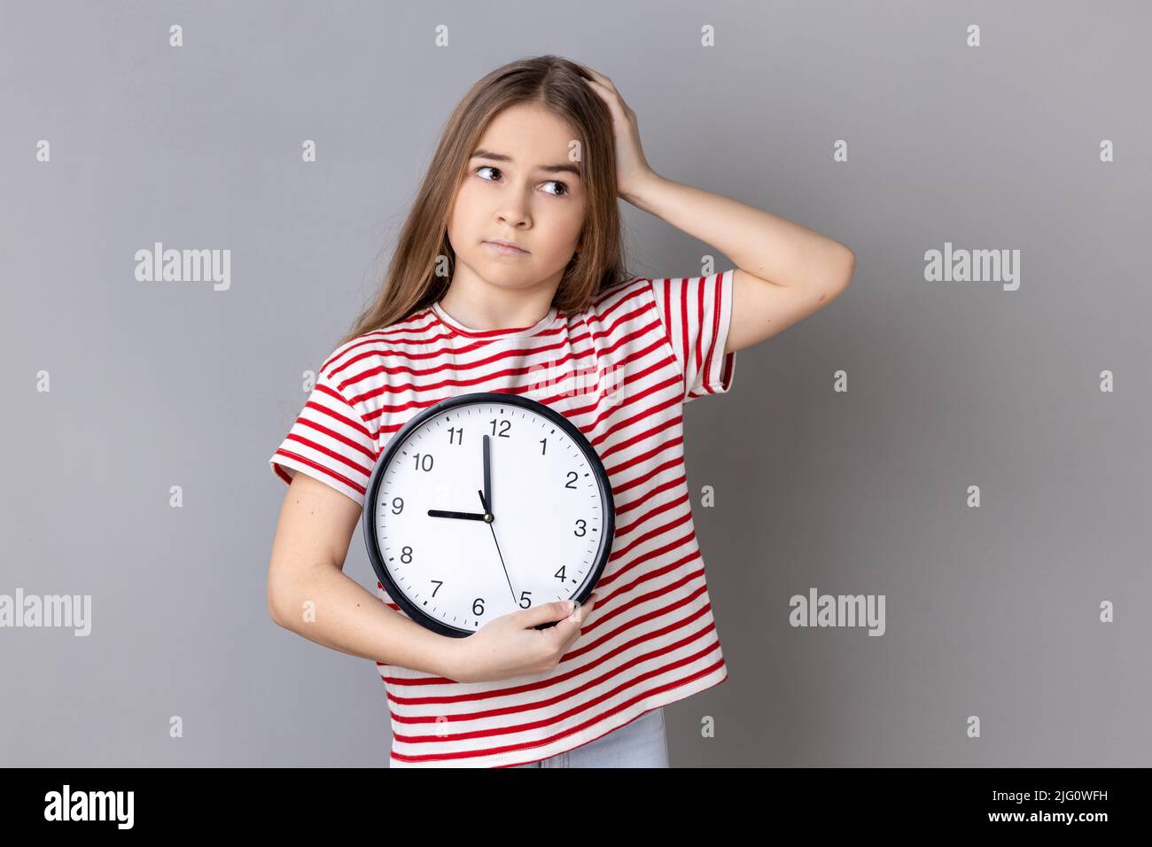 Portrait of confused uncertain little girl wearing striped T-shirt ...
