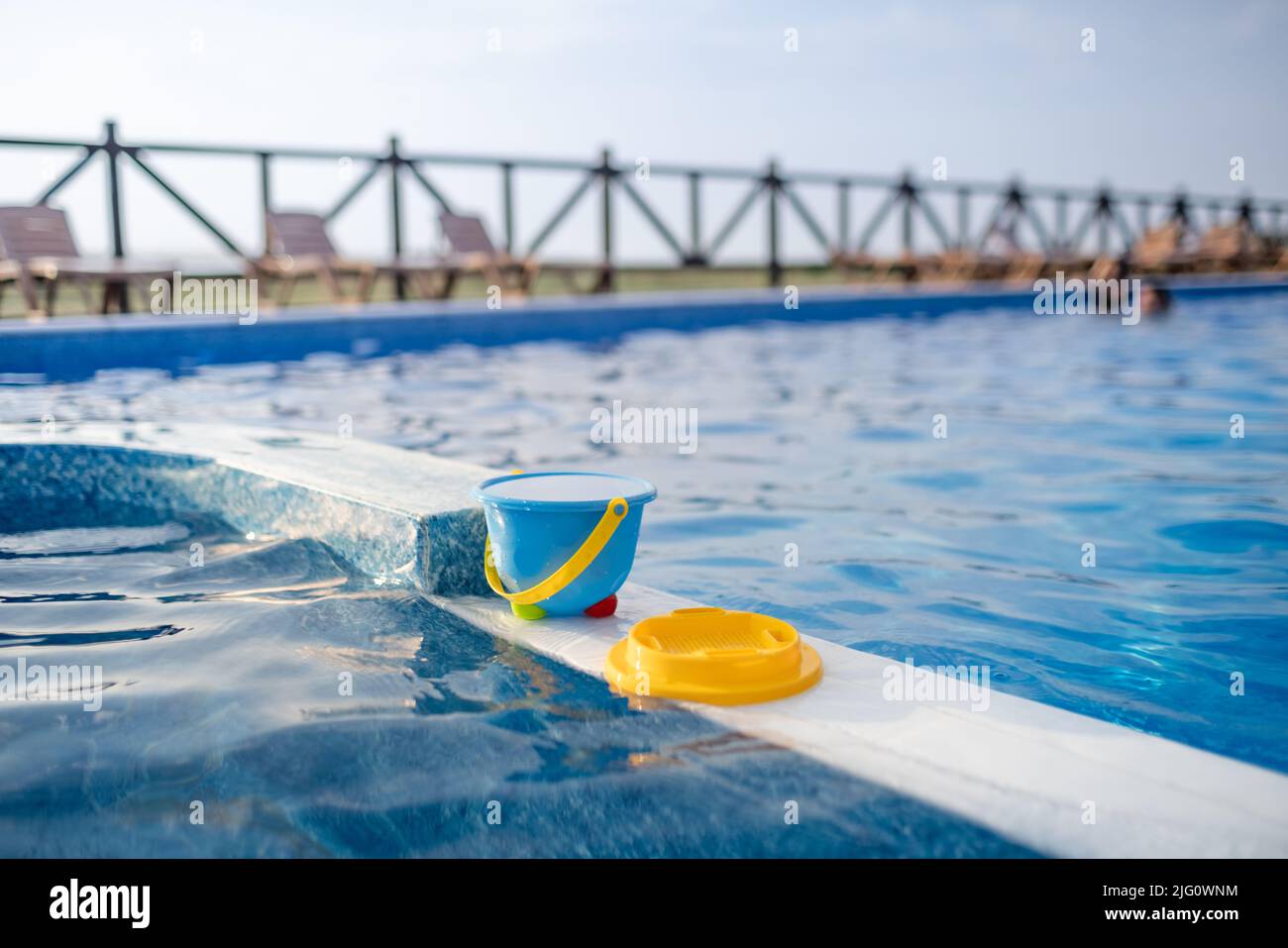 A full children's bucket of water, yellow sieve and some other beach ...