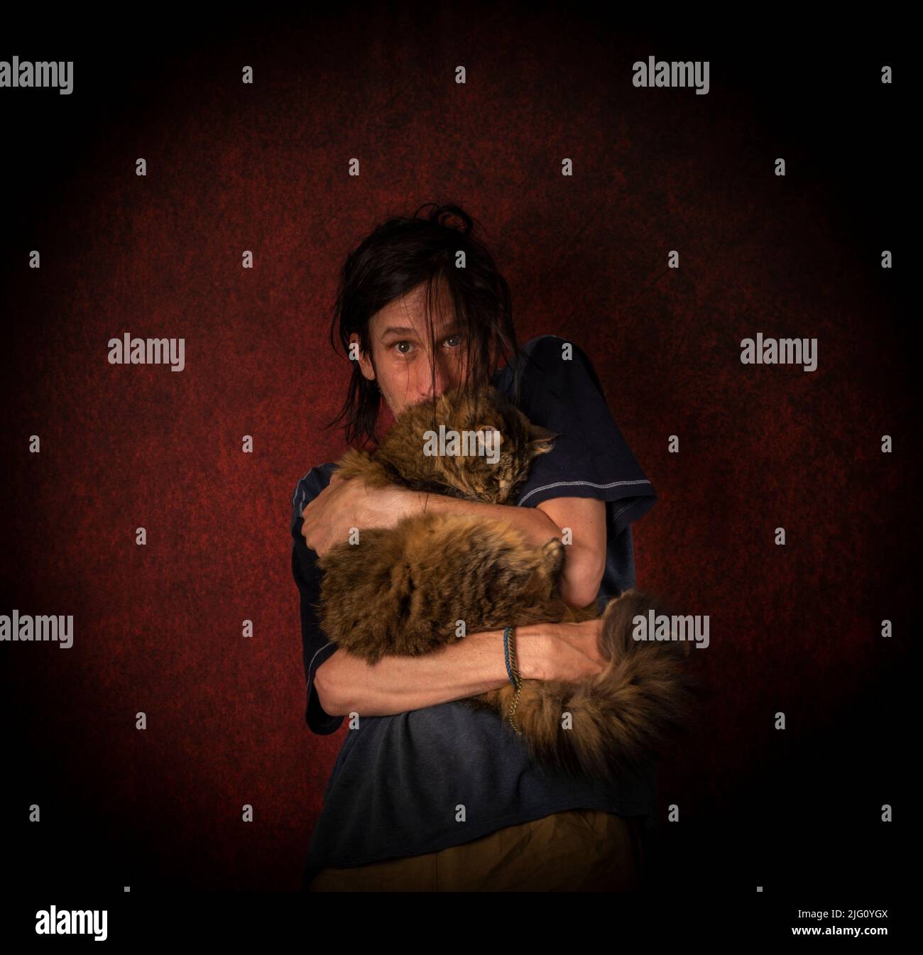 Junkie man with young tabby cat with big green eyes near red wall Stock ...