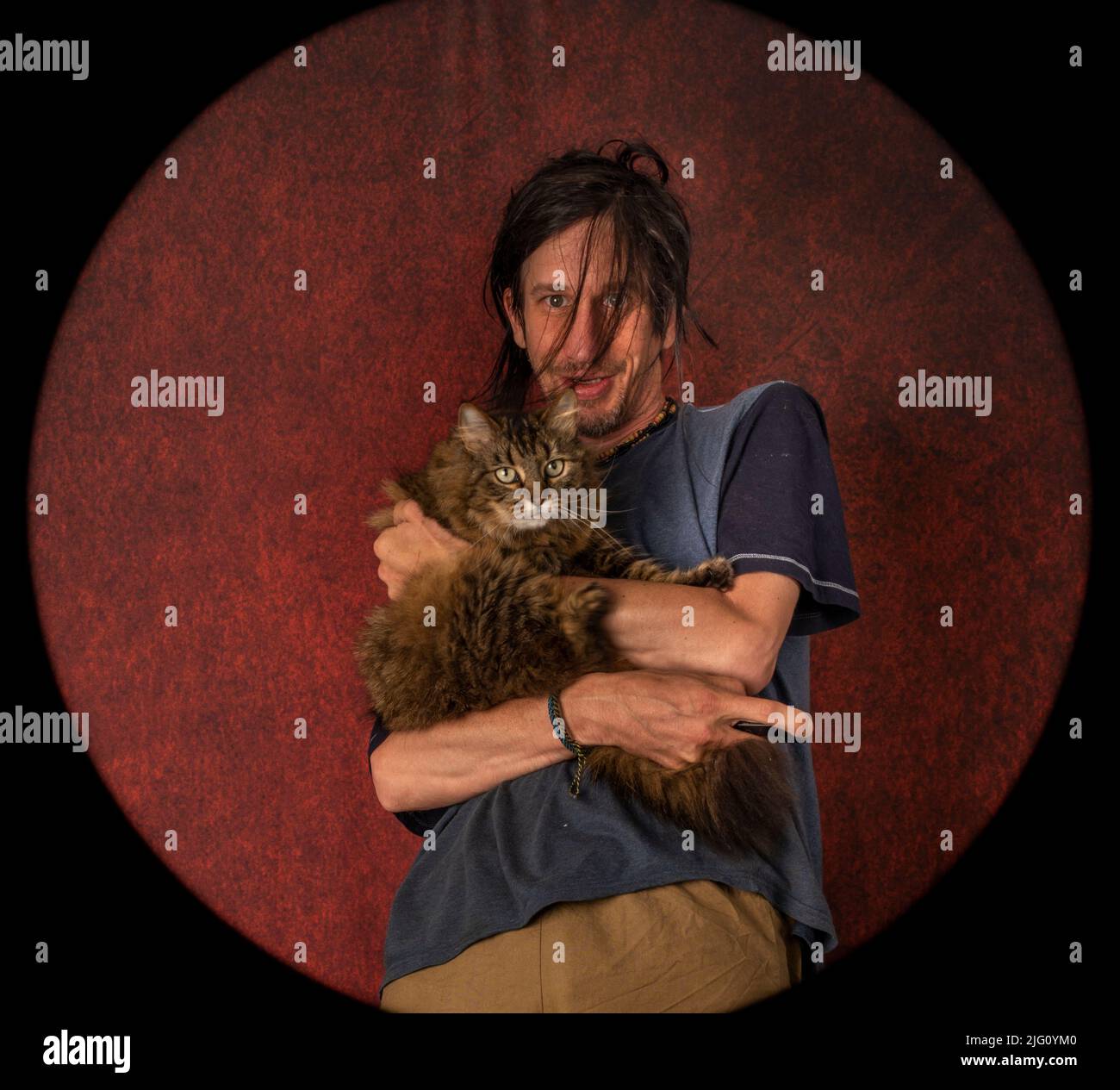 Junkie man with young tabby cat with big green eyes near red wall Stock ...