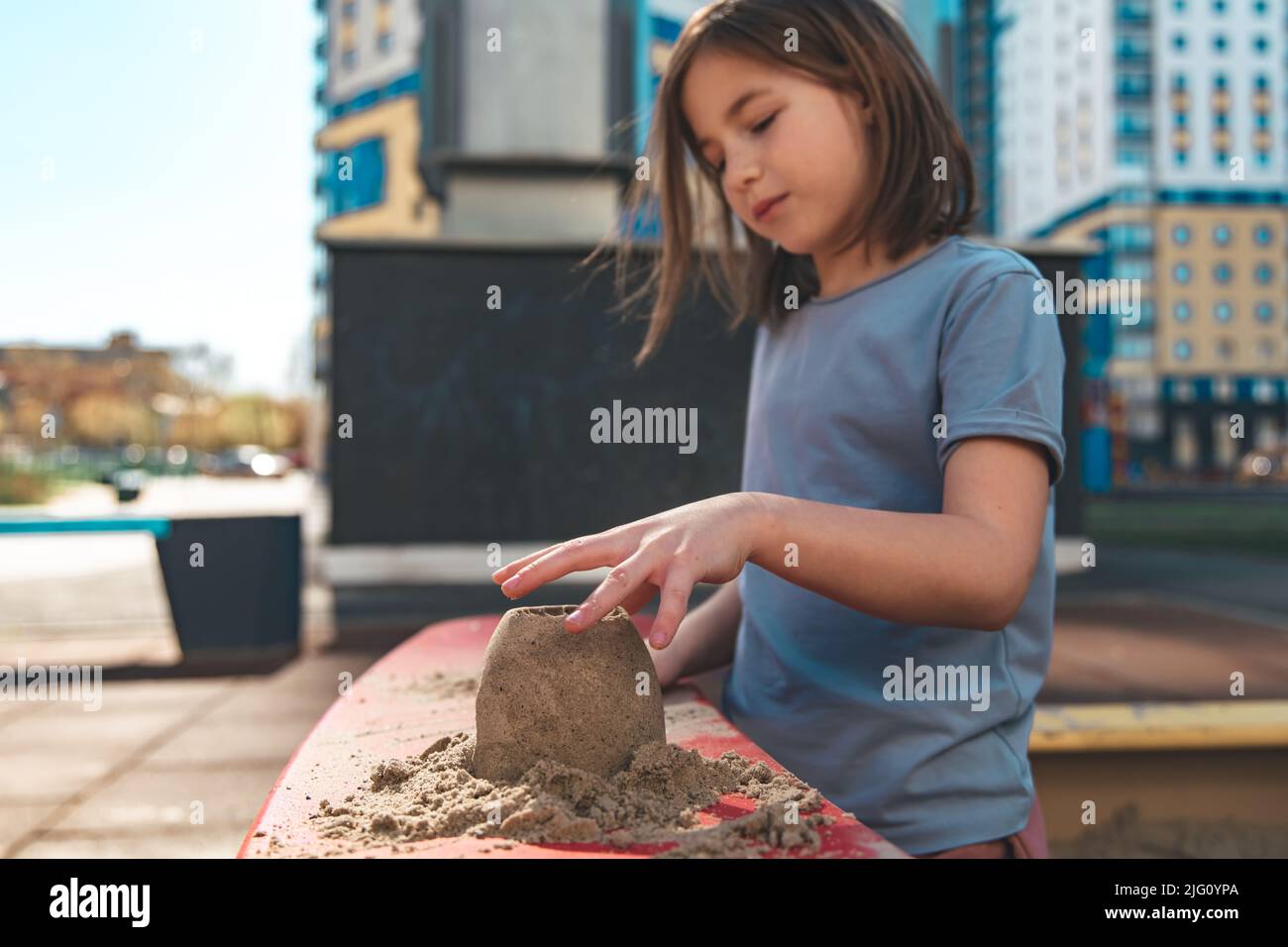 cute girl playing outside in the sandbox and making shapes out of a ...