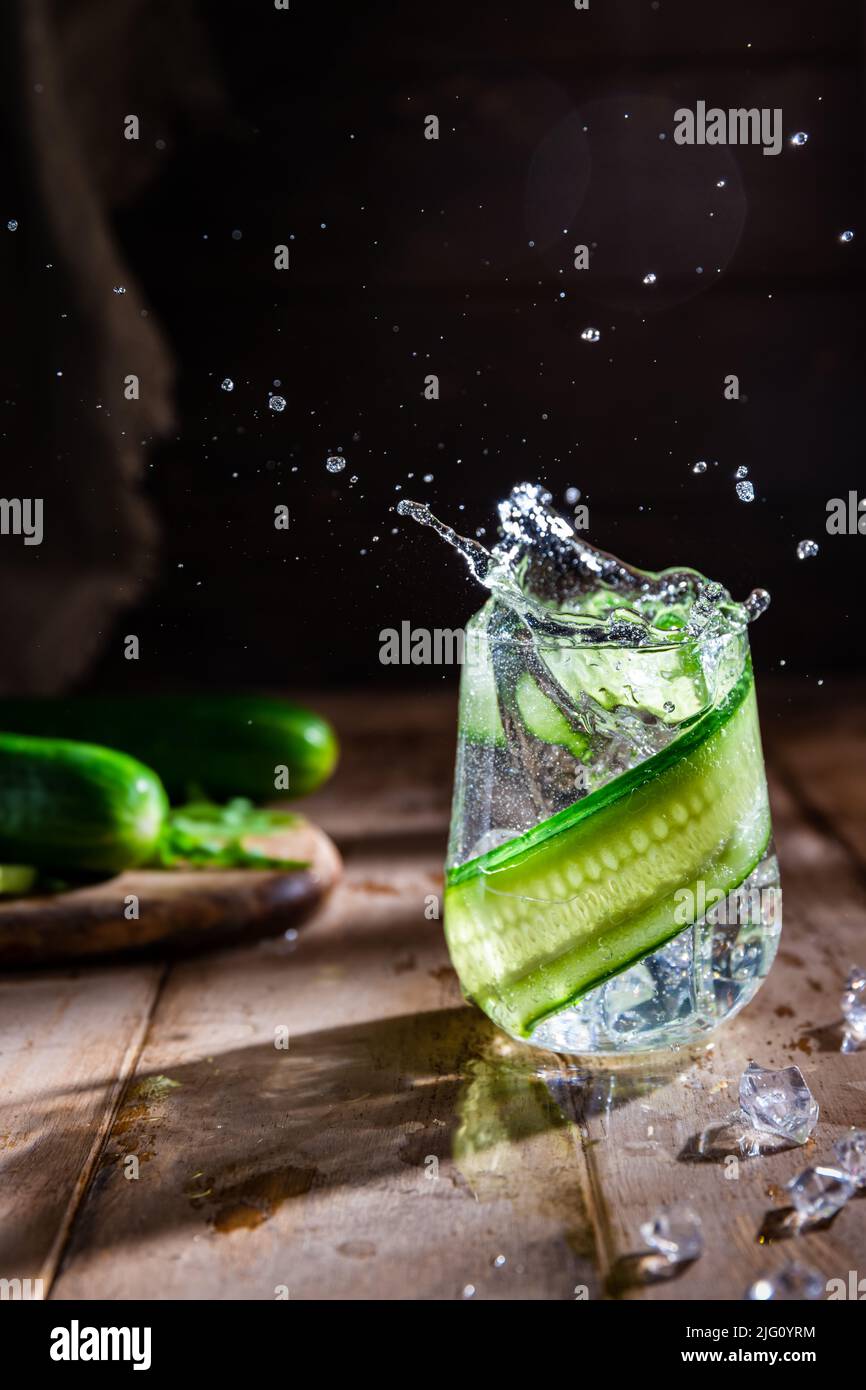 cucumber soft summer drink on a dark background with splashes of water ...