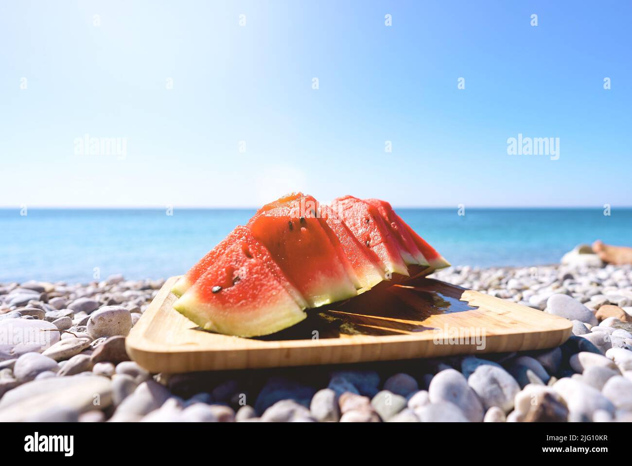 Juicy slices of watermelon on plate. In the background the sea and the ...