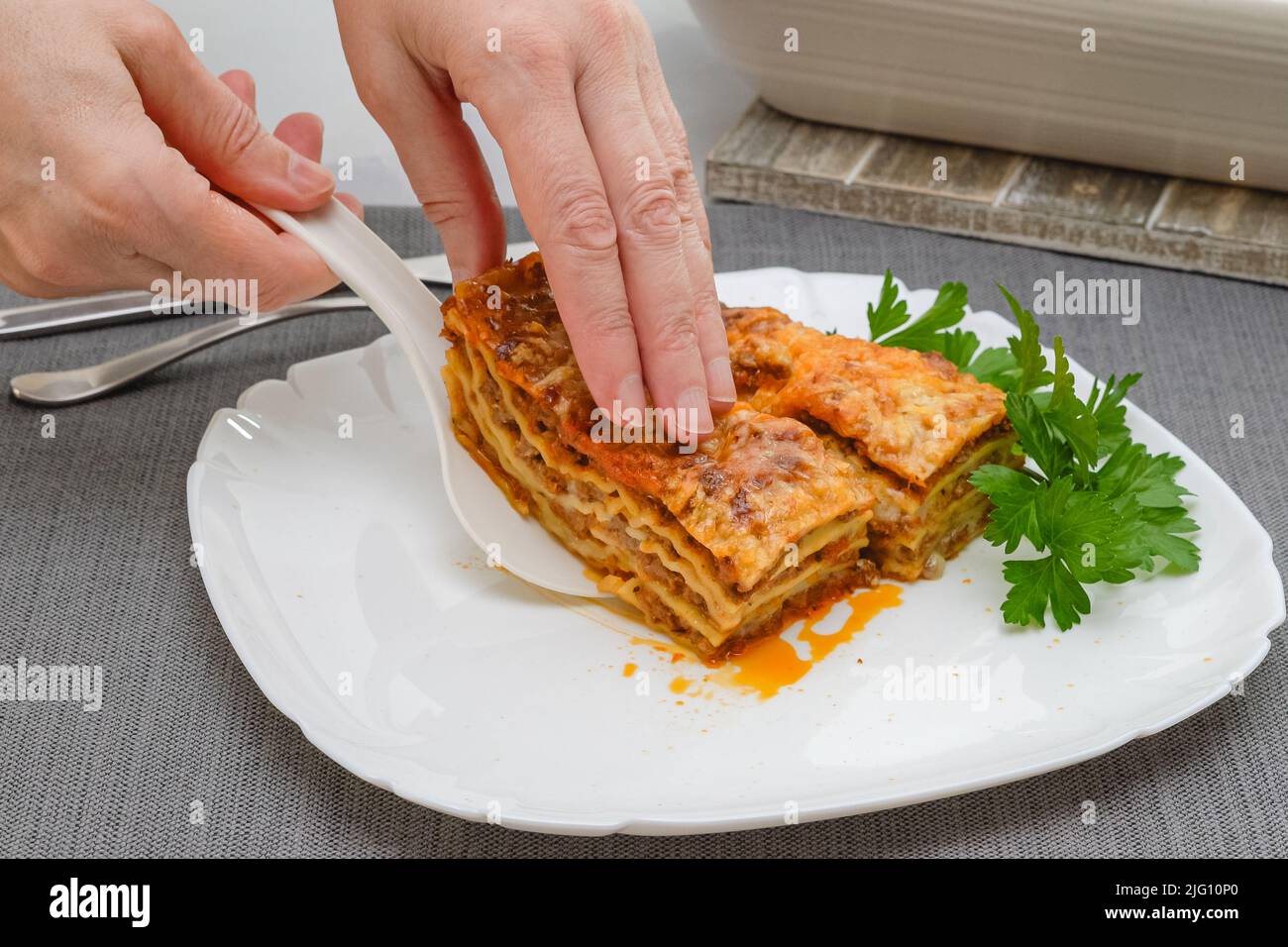 Woman hands serving beef lasagna on a plate, close up view. Homemade ...