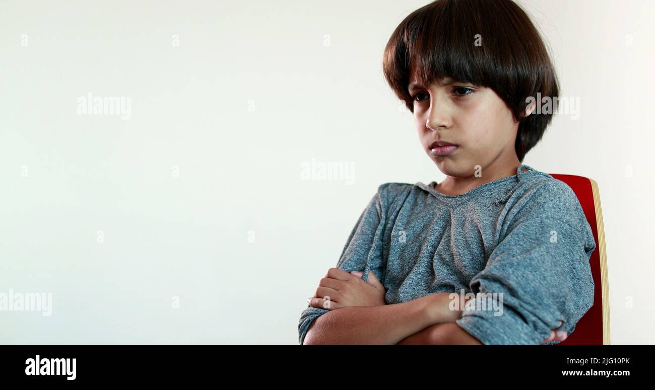 Pensive child boy sitting on chair thinking, kid crossing arms feeling ...