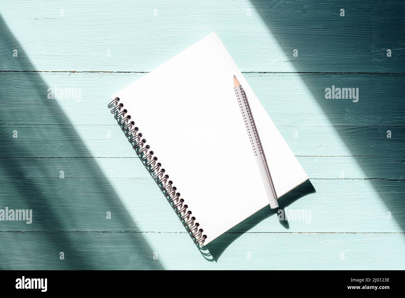Notepad with blank sheet and pencil on turquoise blue wooden table in ...