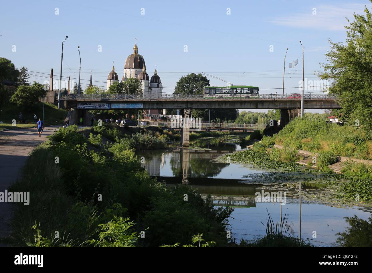 A trolley bus passes over the bridge of the Ustye River with the ...