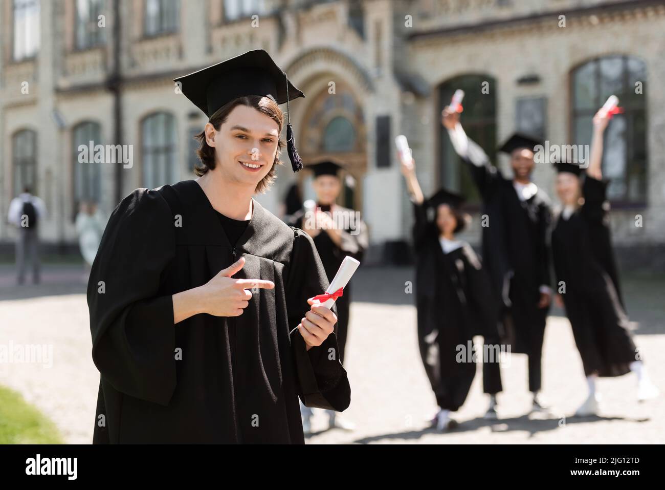 Bachelor in cap pointing at diploma outdoors Stock Photo - Alamy
