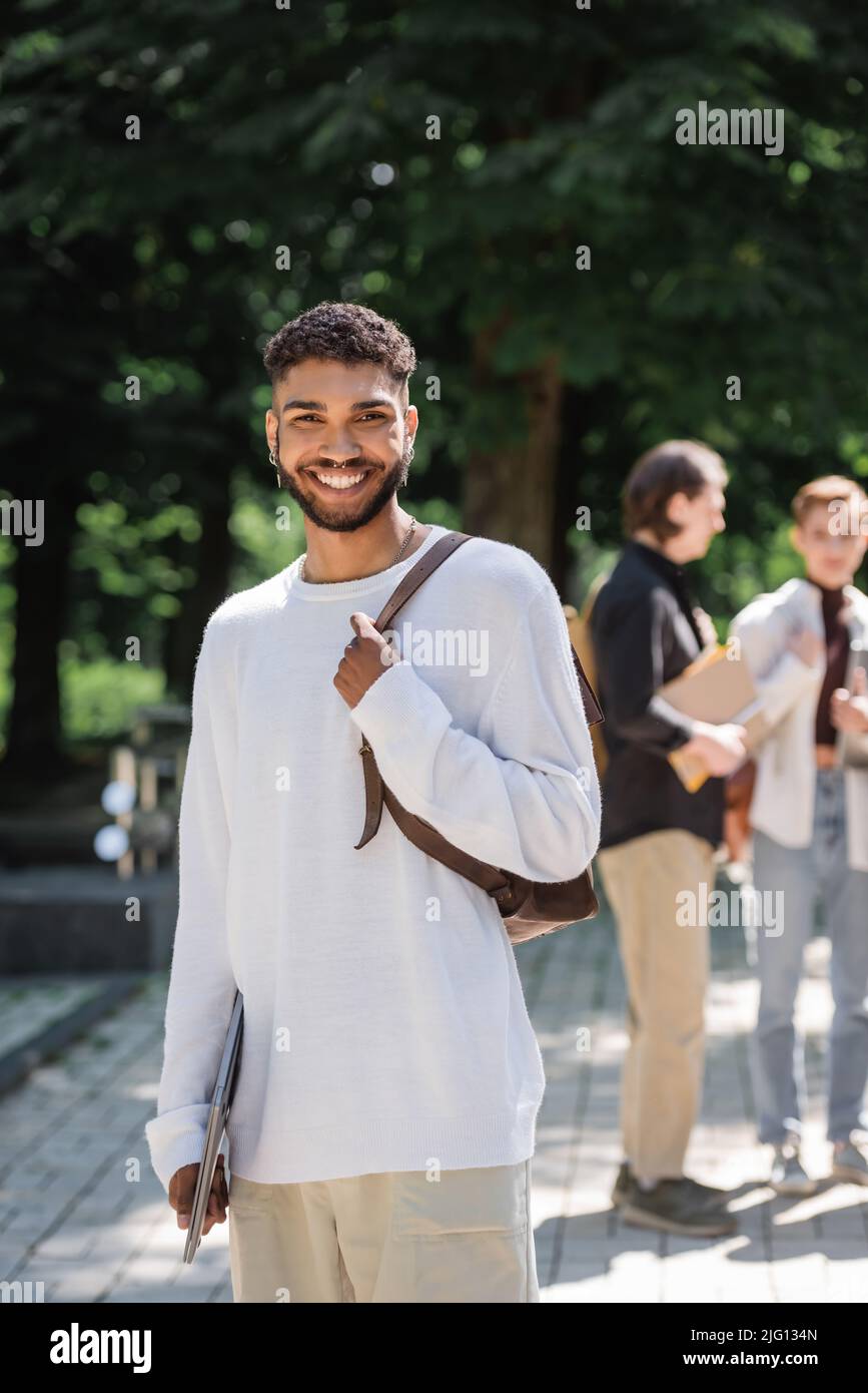 Positive african american student holding laptop and looking at camera ...