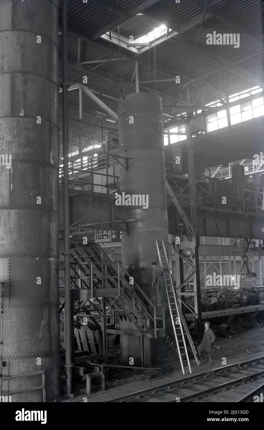 1950s, historical, two steel workers, one on a ladder, inside a giant ...