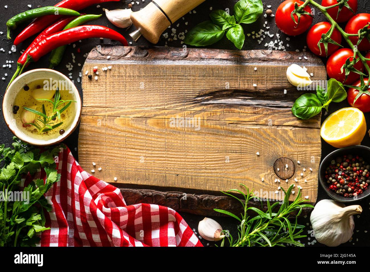 Food background. Oak cutting board, spices and vegetables at kitchen ...