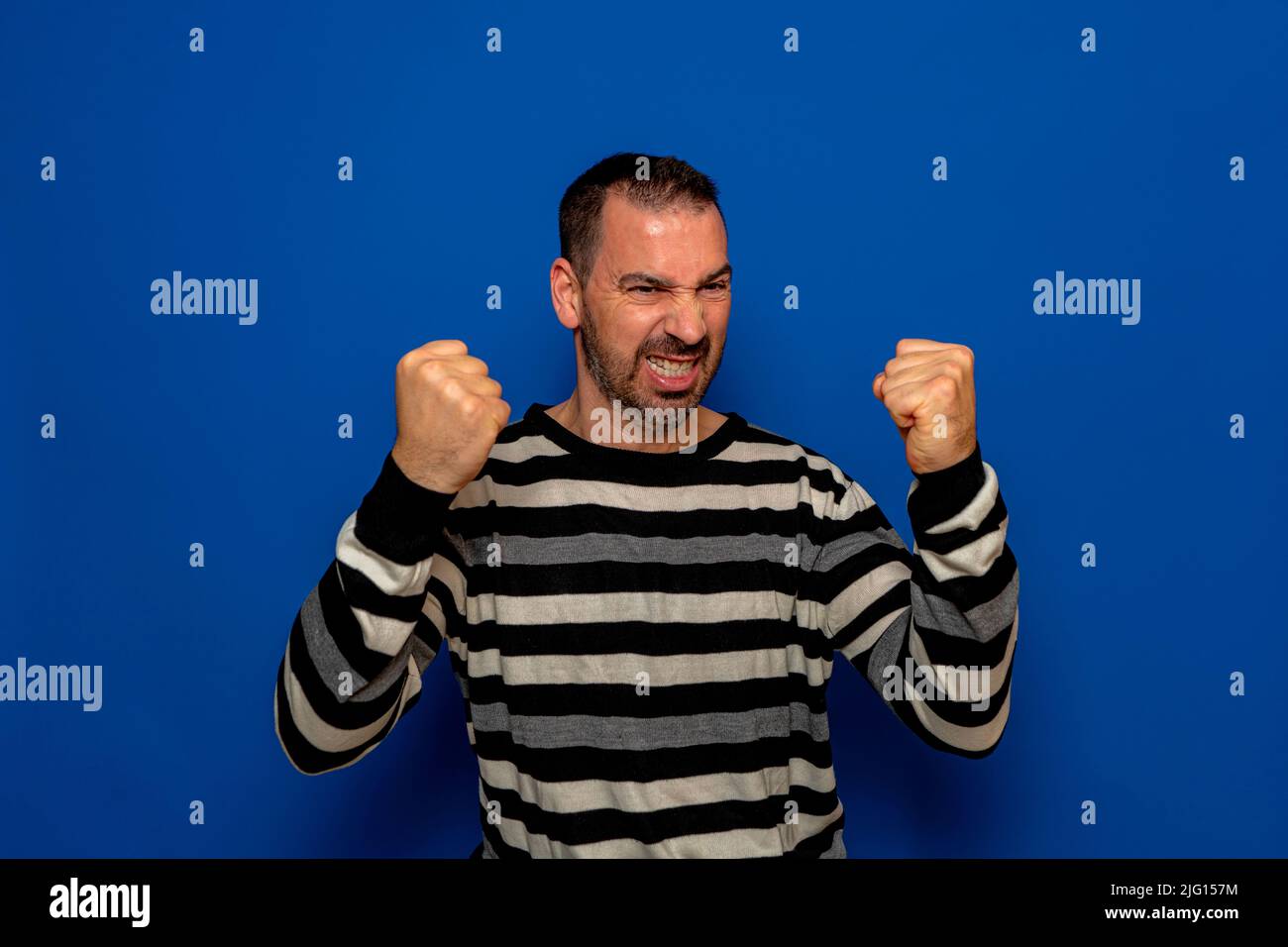 Young hispanic man standing over isolated blue background angry and mad ...