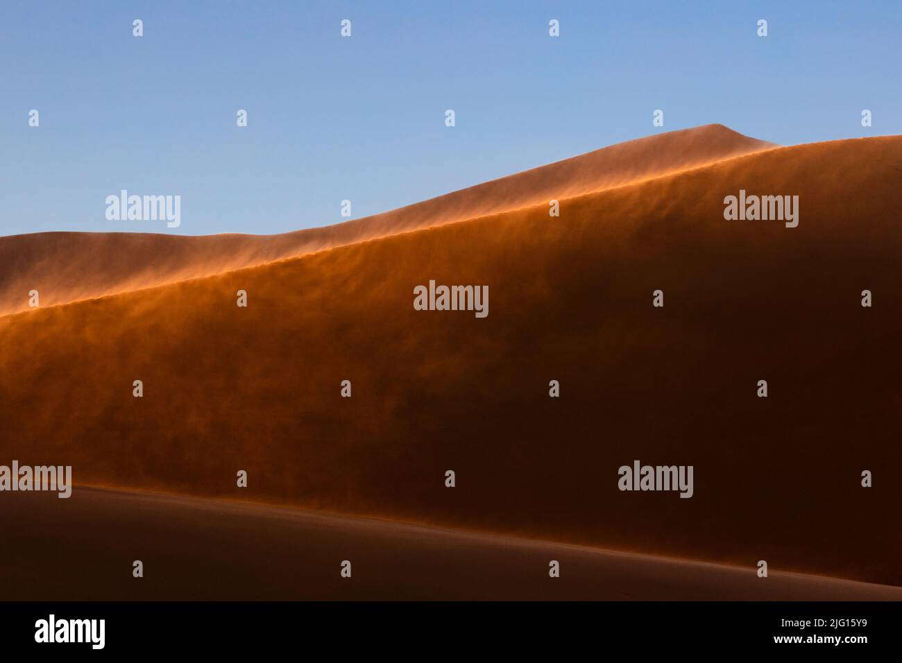 Wind lifting sand along the crest of a dune in the Namib Desert on the ...