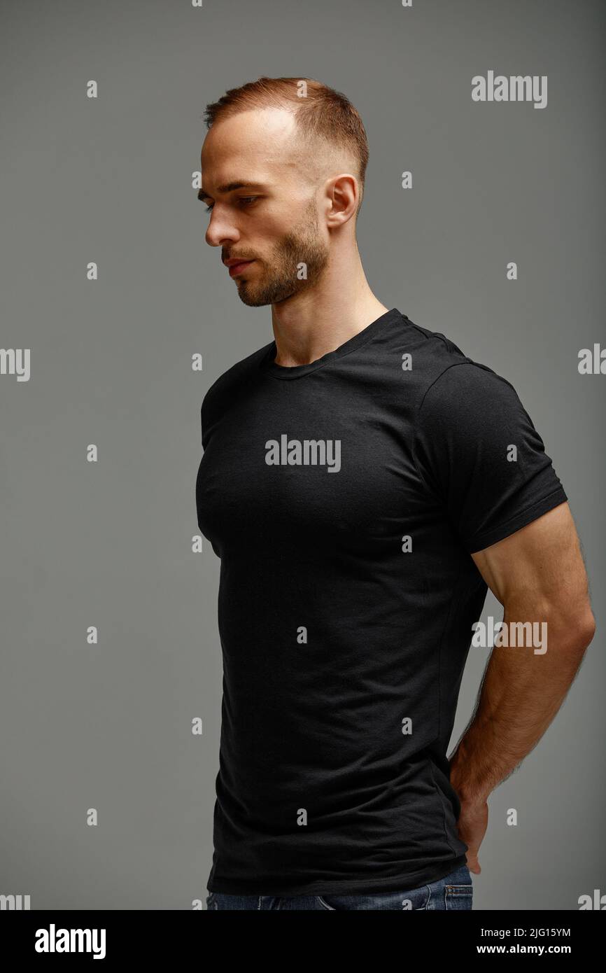 An attractive white man in jeans and black shirts tands in half growth ...