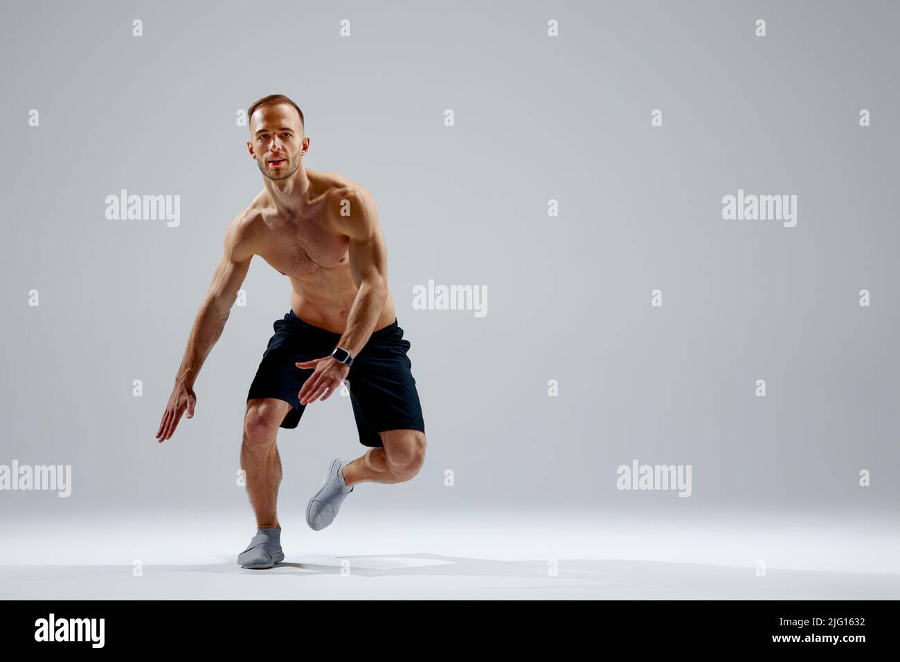 Developing endurance. Male athlete in motion isolated over gray studio ...