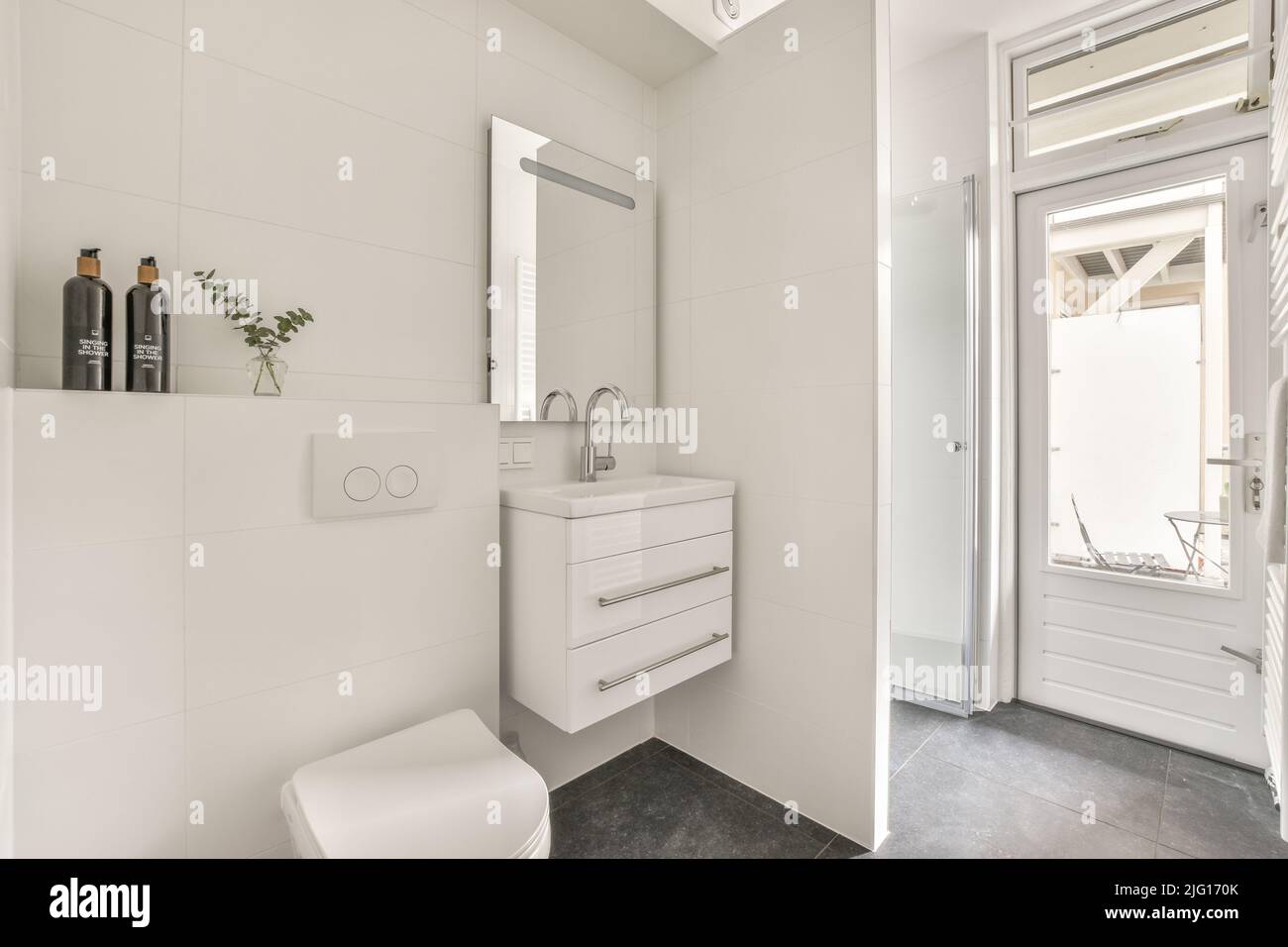 Modern Flush Toilet And Ceramic Sink Installed On White Tiled Walls