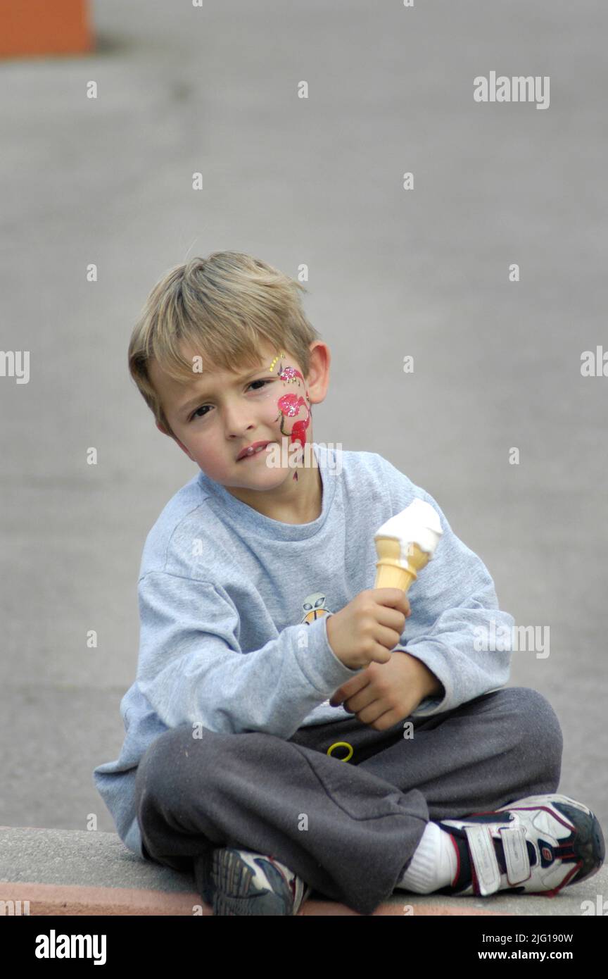 Young boy with face paint eating Ice Cream Cone soft white, with copy ...