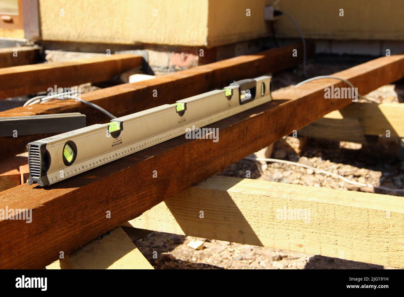 Level check of a wooden beam. Building level in use Stock Photo - Alamy