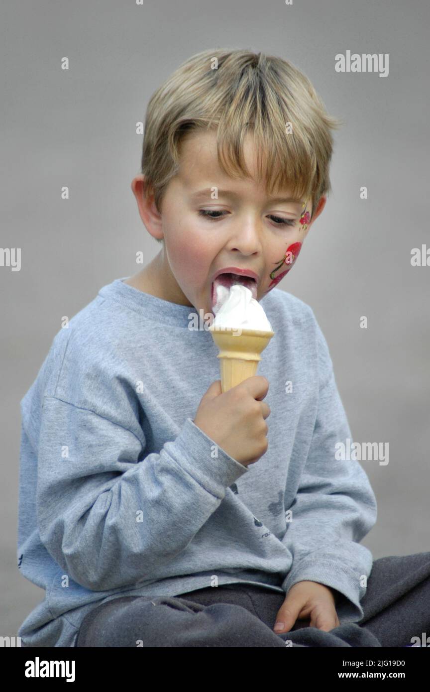 Young boy with face paint eating Ice Cream Cone soft white, with copy ...