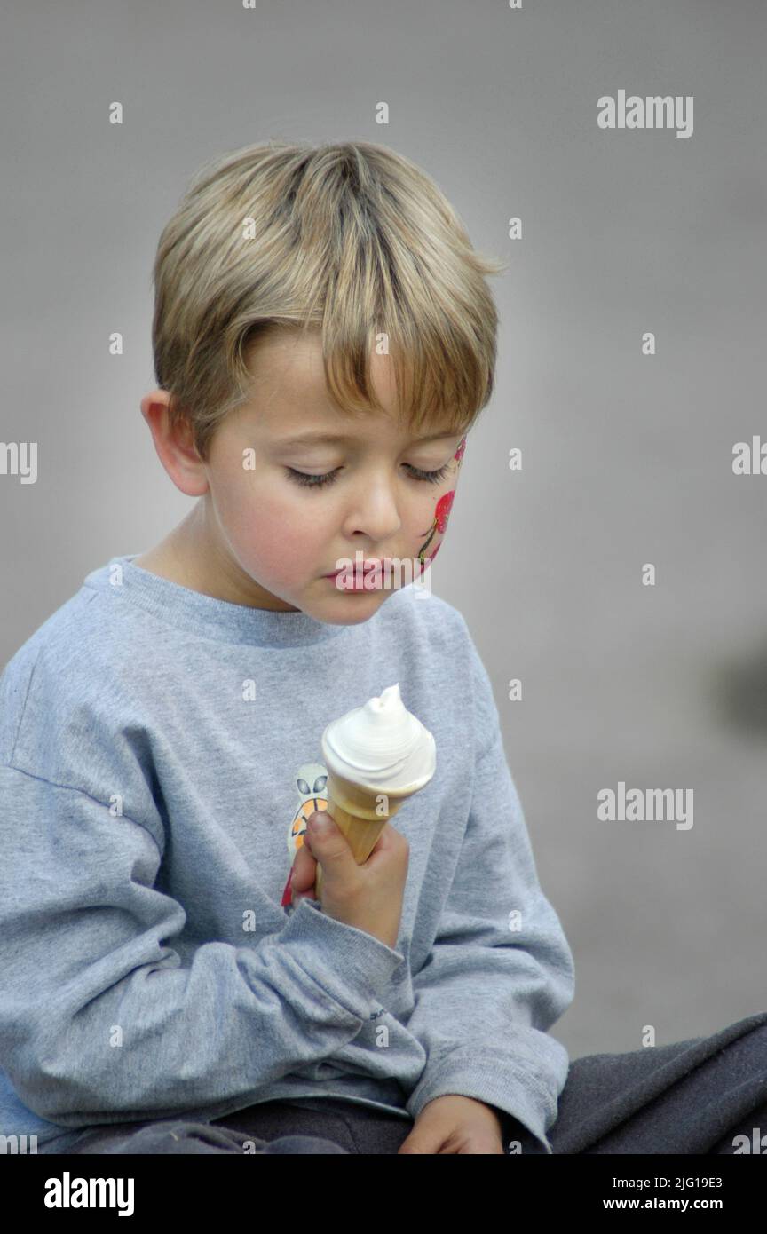 Young boy with face paint eating Ice Cream Cone soft white, with copy ...
